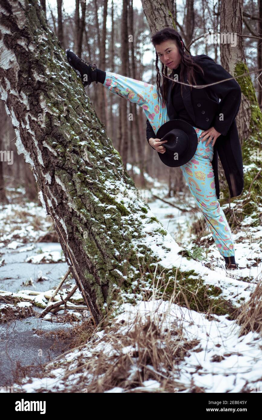 Dancer makes cheeky pose with hat against snow covered tree in germany ...