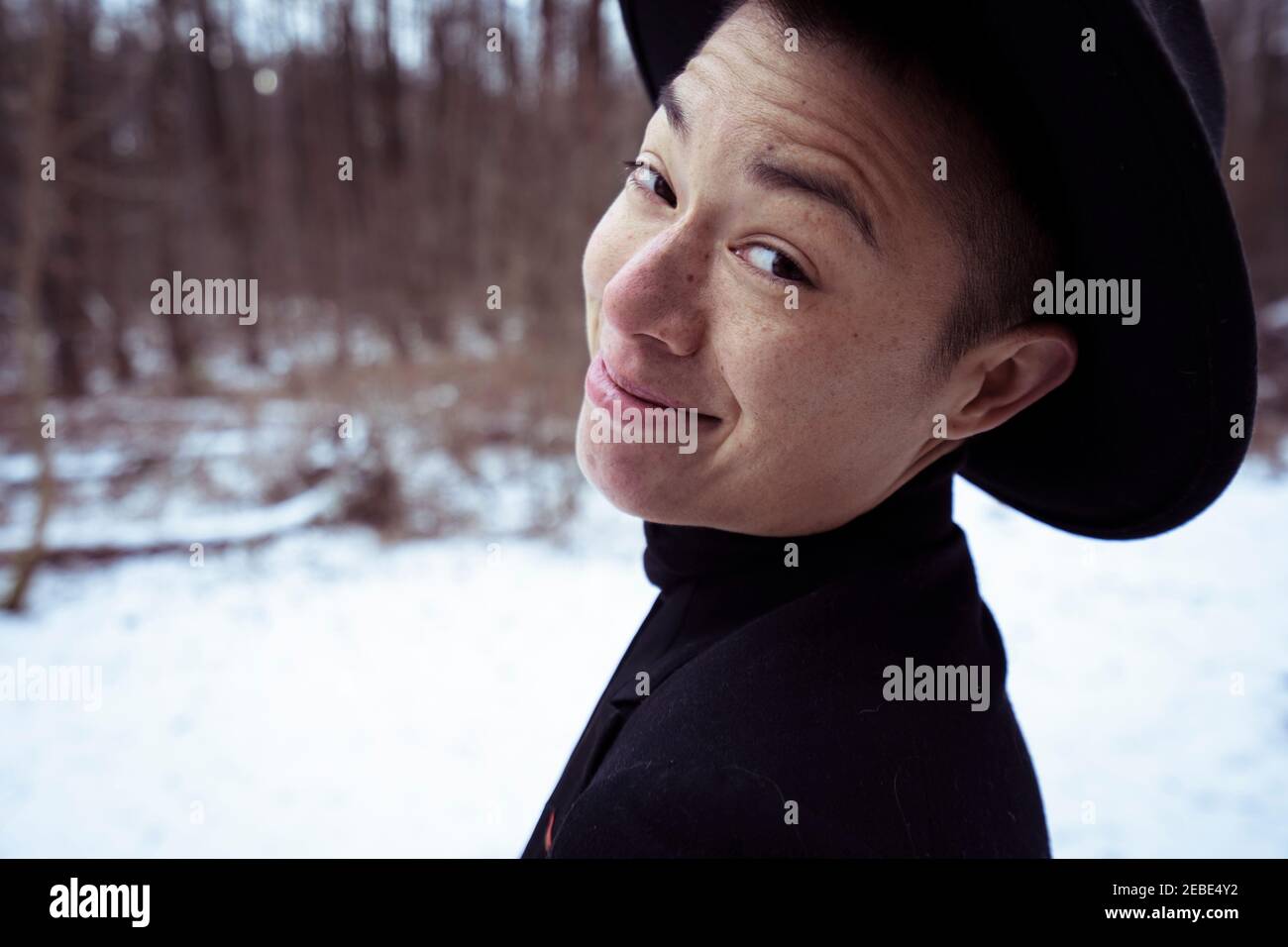 big cheeky smile from mixed-race person in black hat on white snow ...