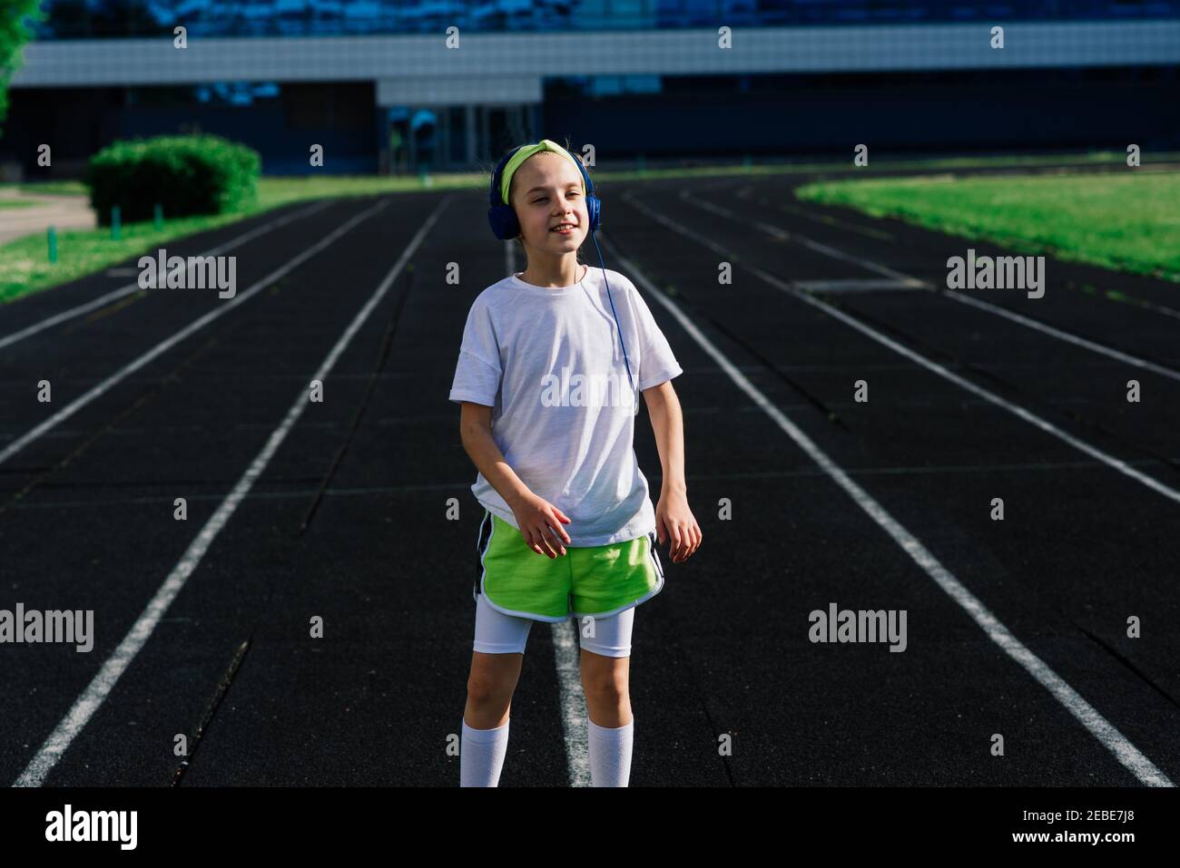 Girl jogging on a sunny summer evening, laying on treadmill, stadium ...