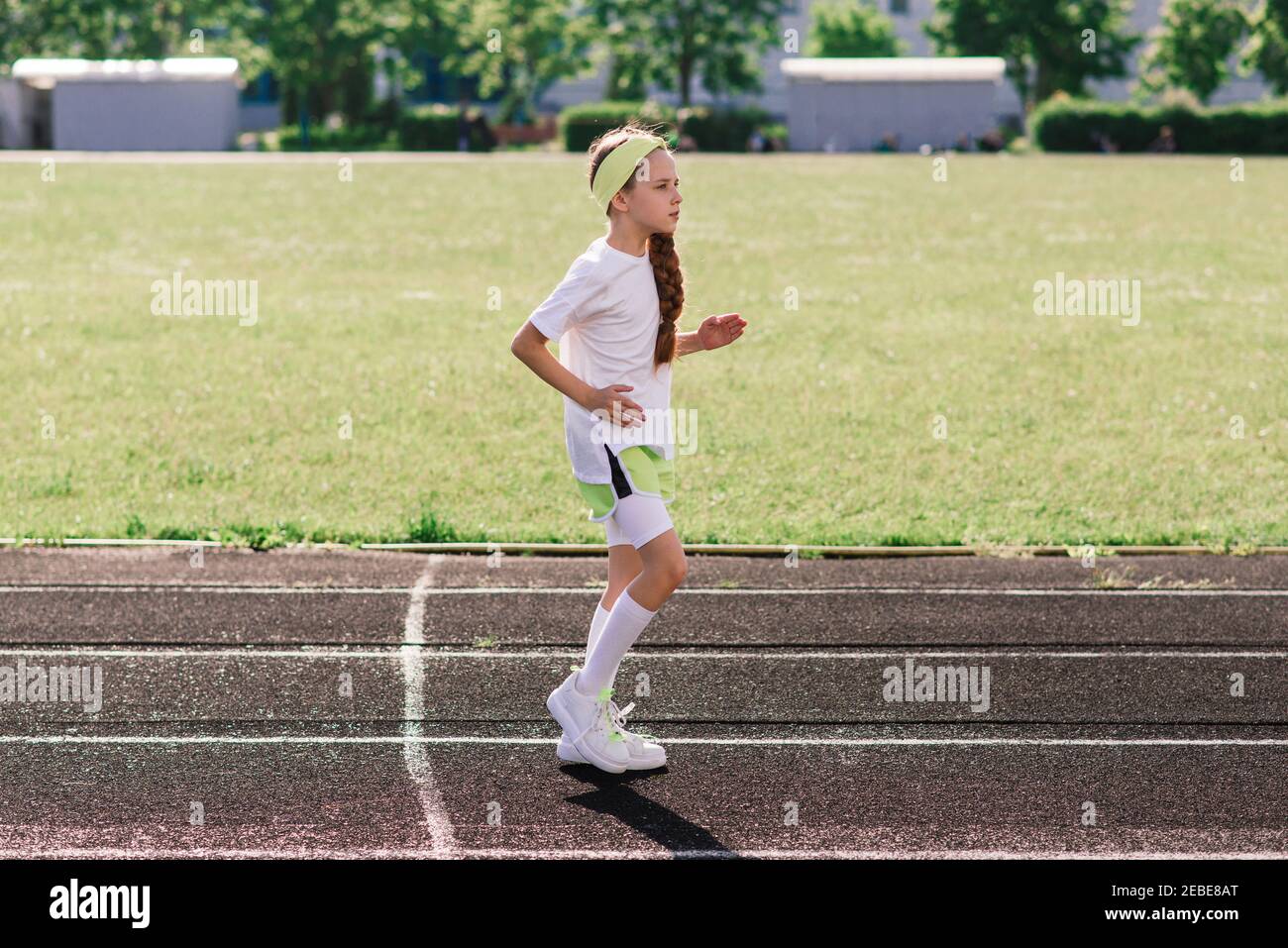 Girl jogging on a sunny summer evening, laying on treadmill, stadium ...