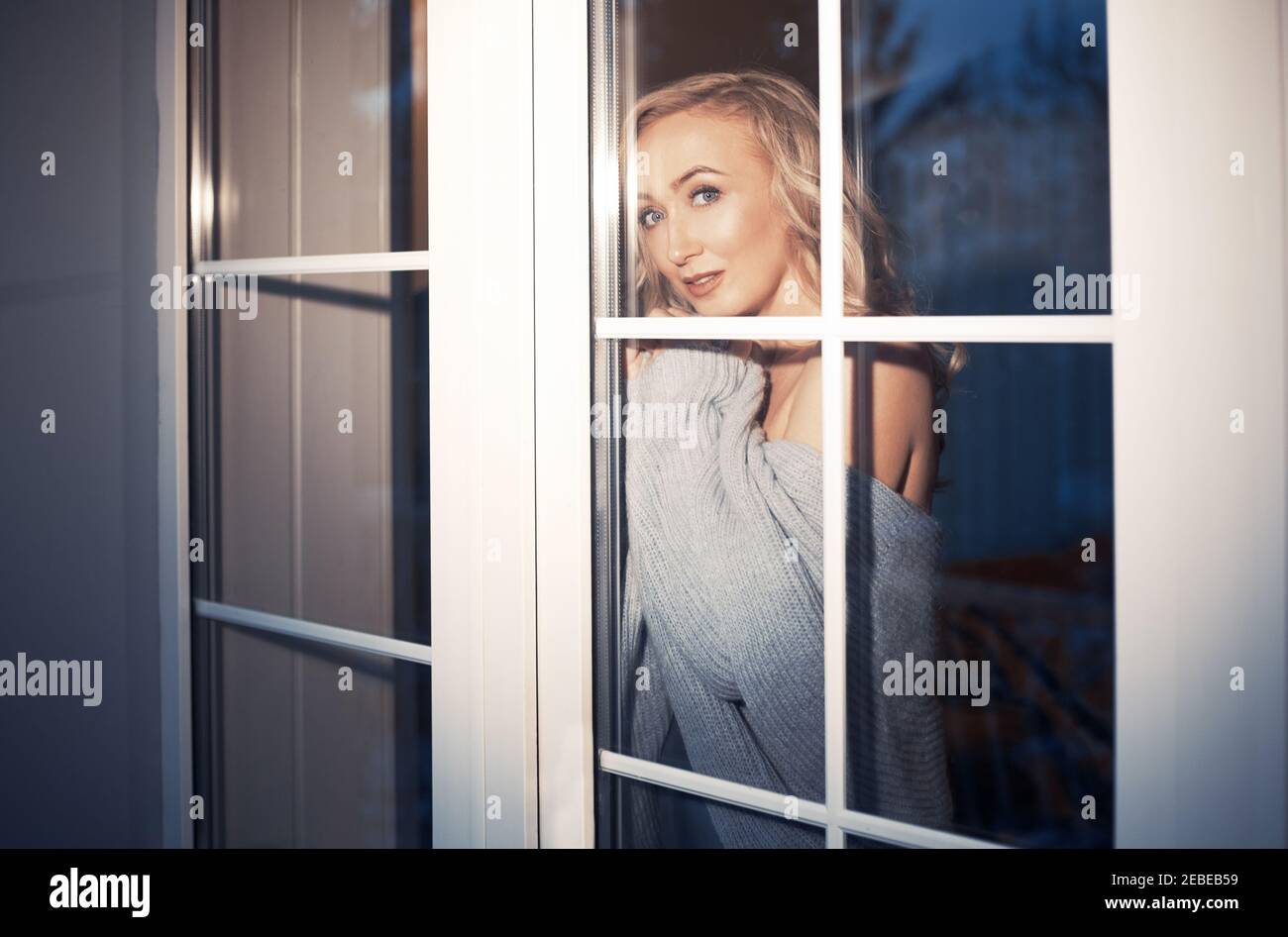 Blond woman behind the window Stock Photo - Alamy
