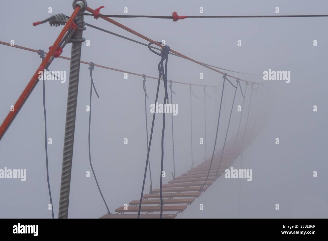 suspension bridge over an abyss into fog Stock Photo - Alamy