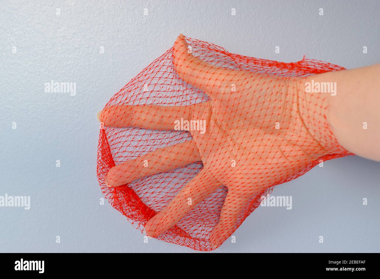 Female hand in red net, symbol of restricted movement, pain, virus ...
