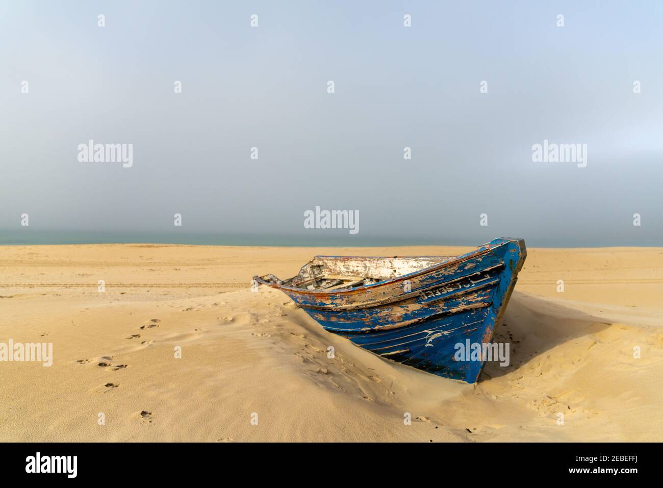 colorful wreck of an old wooden rowboat buried in the sand with an ...