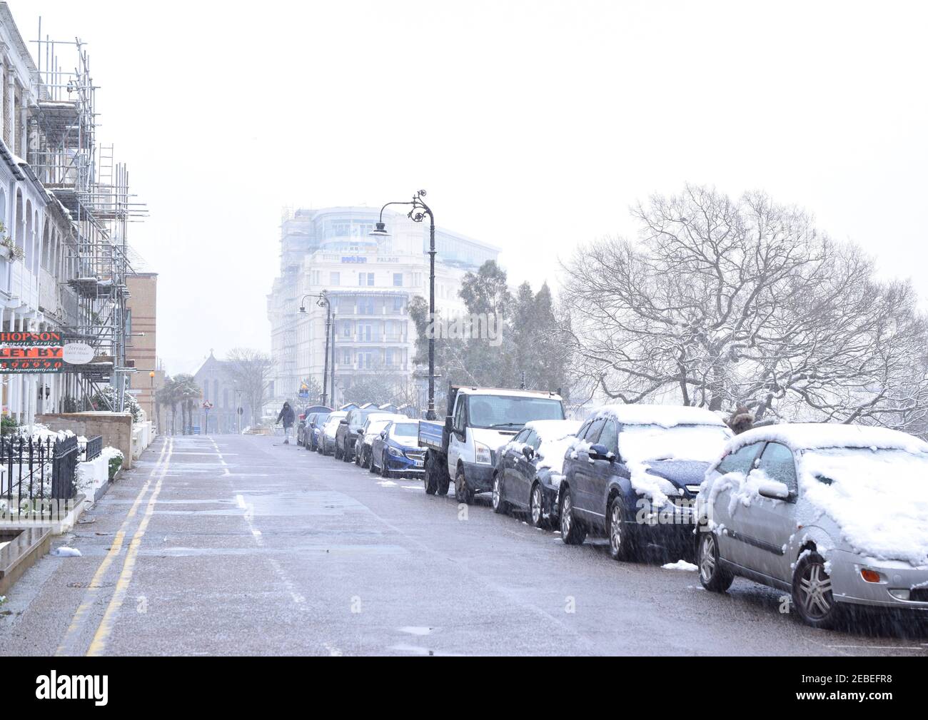 Street view with cars, trees and buildings covered in snow in England ...