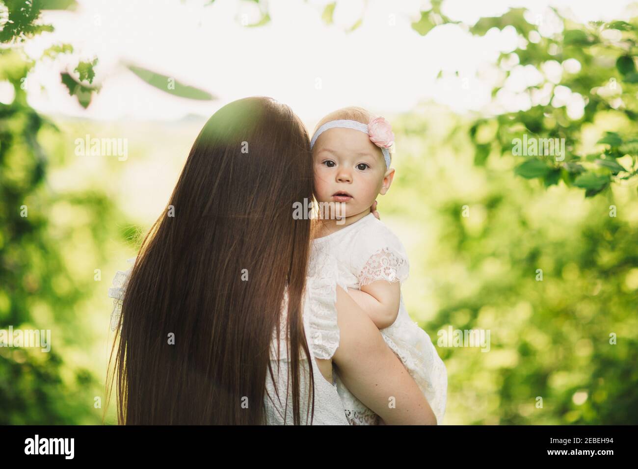 Mother and child daughter walking in spring garden. Young woman and ...