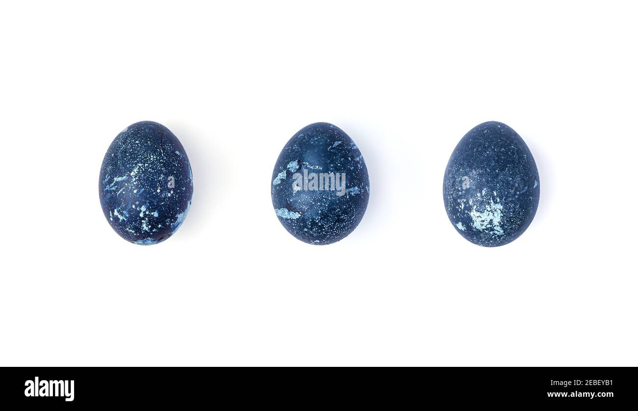 The three eggs are colored with natural dyes with a dark blue color on ...