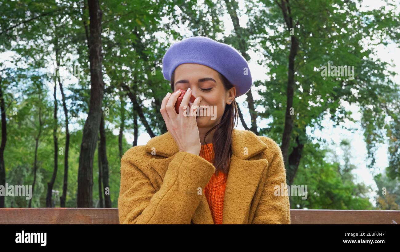 pleased woman smelling ripe apple with closed eyes in park Stock Photo ...