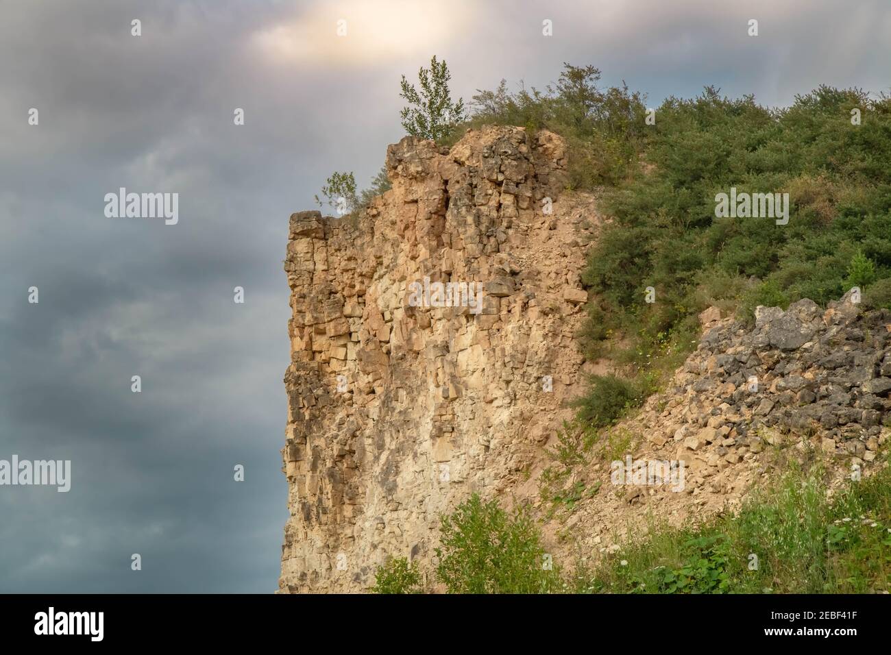 High cliff after mining on dramatic cloudy sky background. Exploitation ...