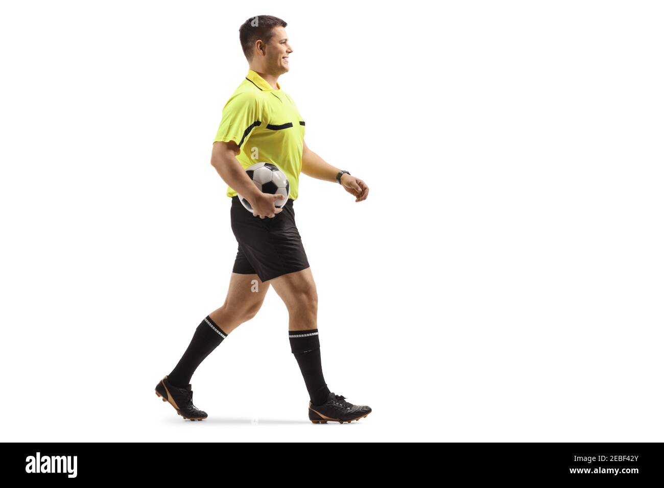 Full length profile shot of a referee holding a football and walking ...
