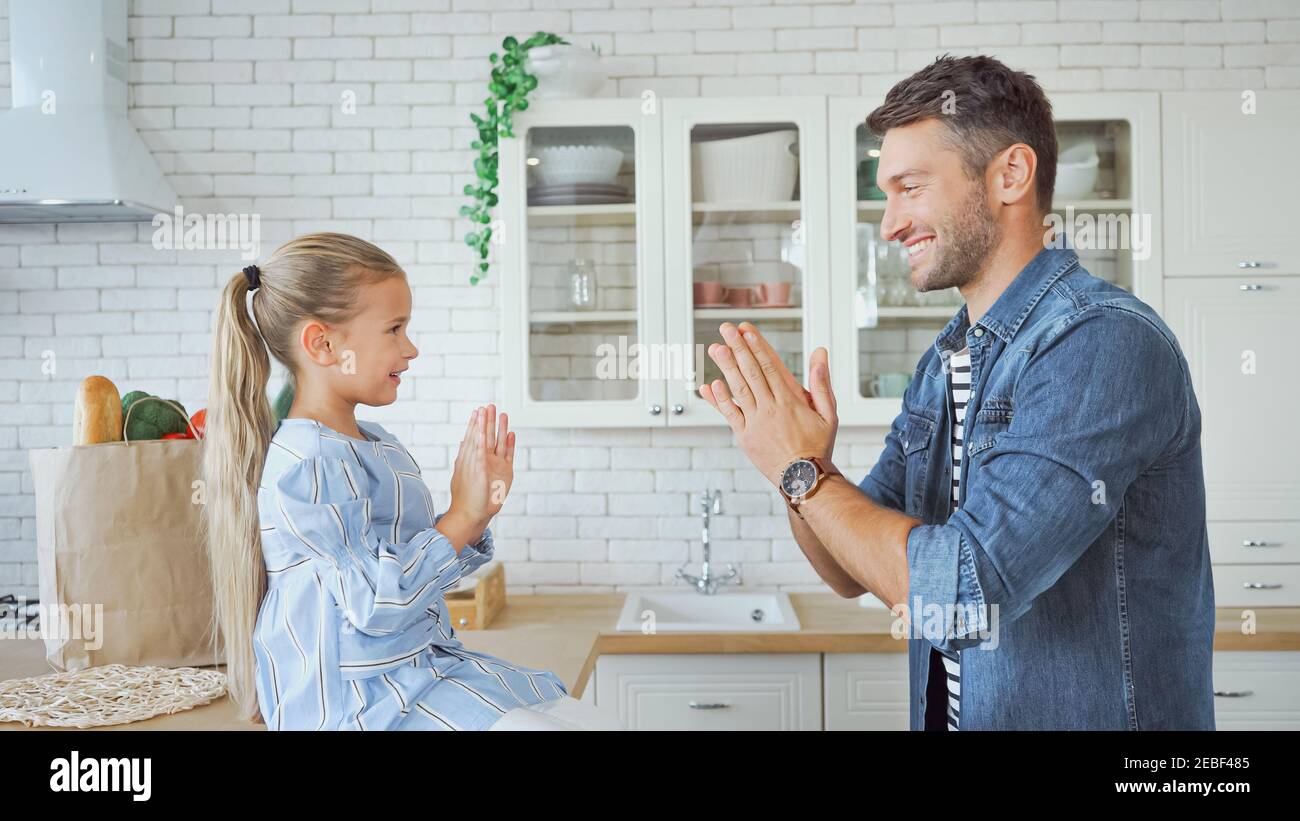 Side view of smiling father and daughter playing patty cake game in ...