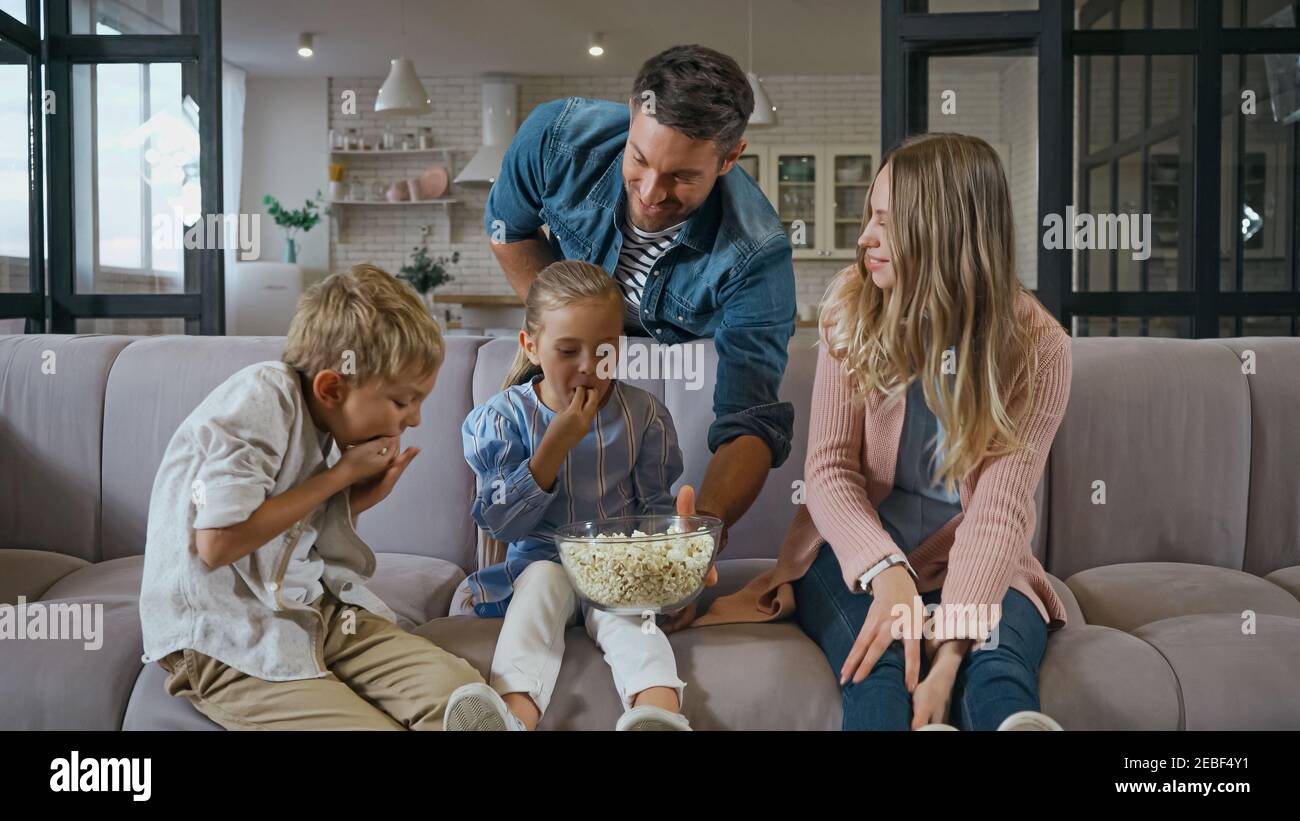 Kids eating popcorn near smiling parents on couch Stock Photo - Alamy