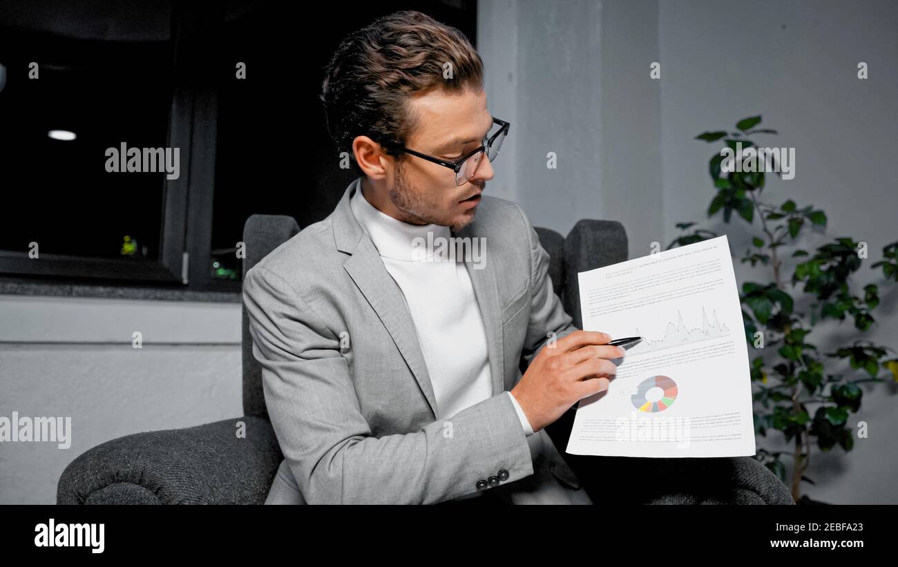 Young businessman pointing at paper with charts in office Stock Photo ...