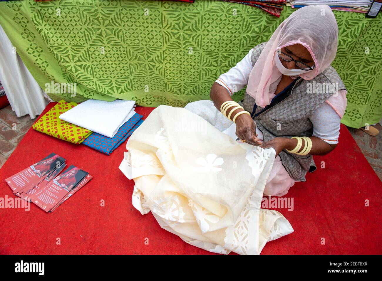 A woman from the Bheel Tribe seen making applique and tanka on a cloth ...