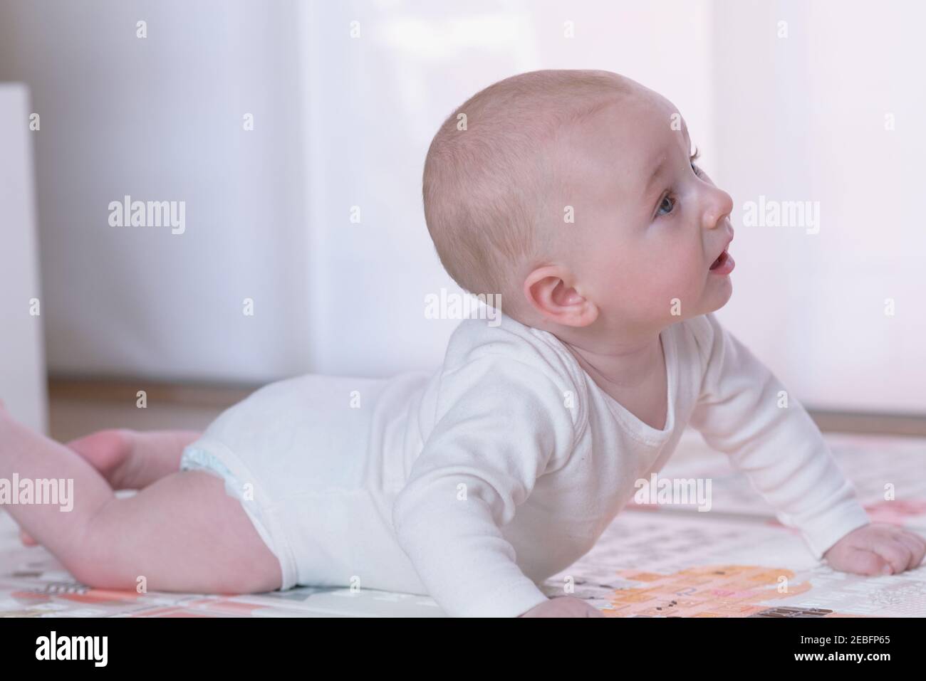Baby crawling indoors smiling. Family life Stock Photo - Alamy