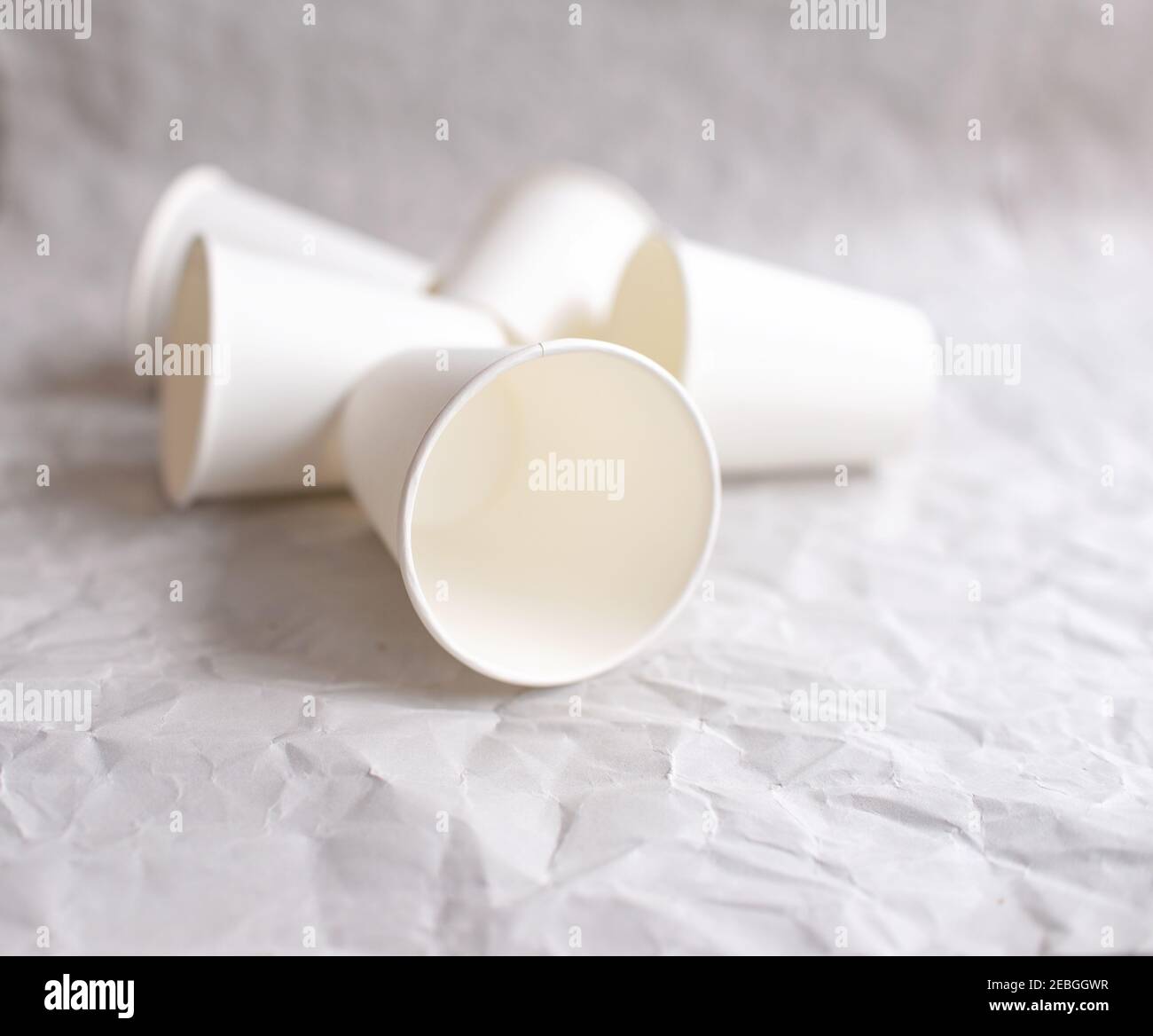 disposable cups made of white paper are laid out on gray crumpled paper ...