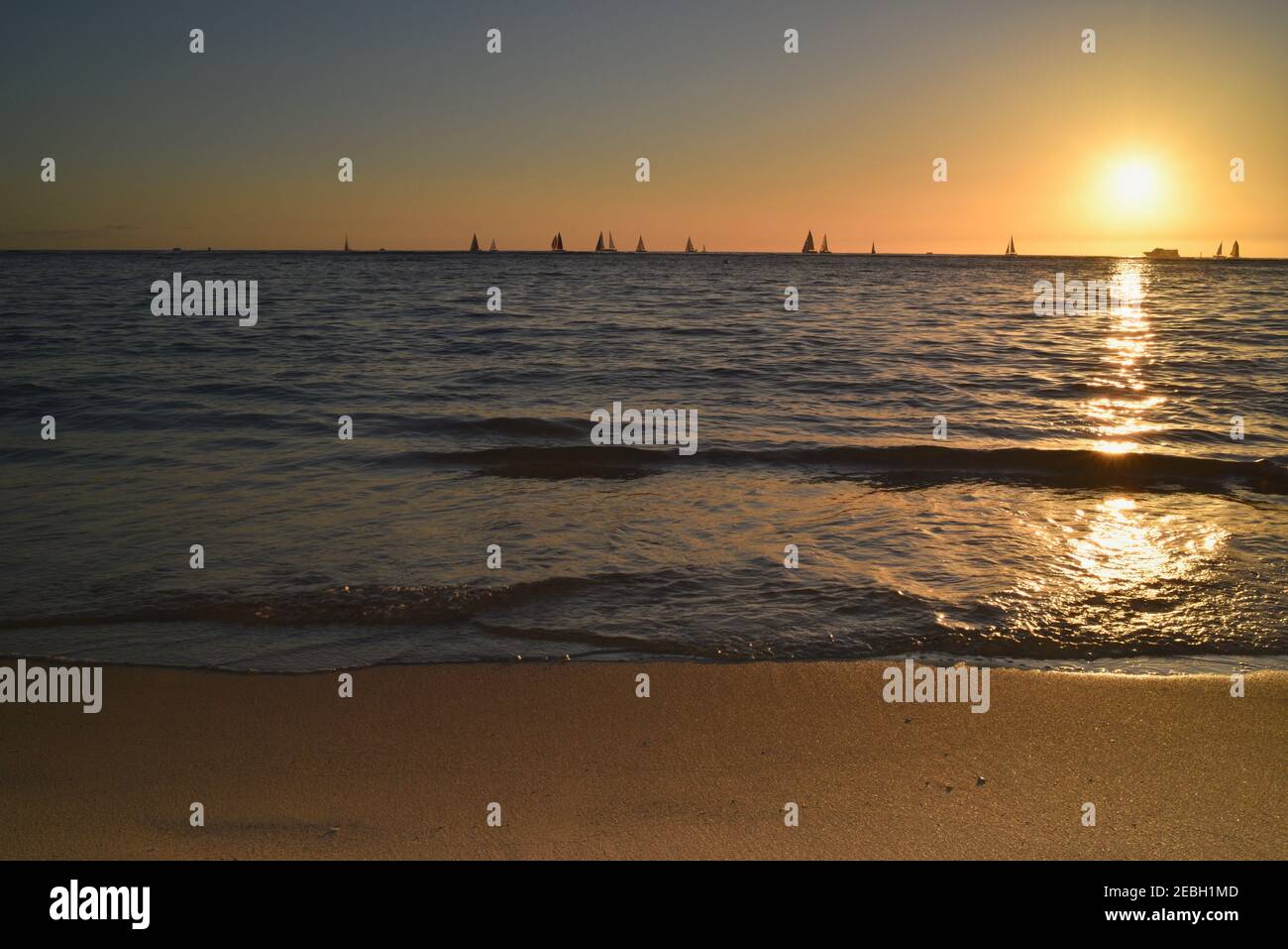 Spectacular sunset on the Waikiki Beach, with distant sailboats on ...