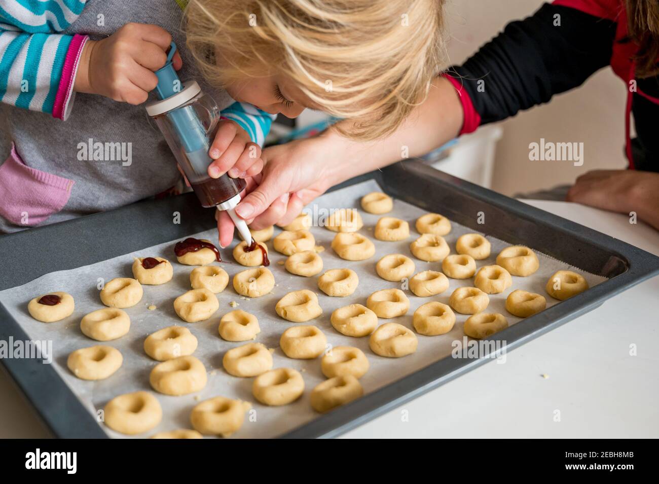 Cute blonde girl making cookies with her mother Stock Photo - Alamy