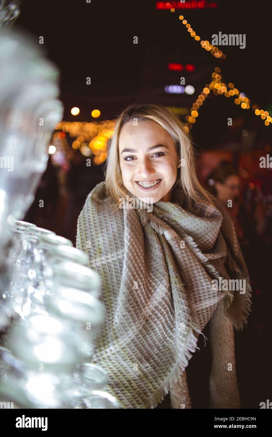 Blonde young lady posing for the camera behind the lights in the night ...