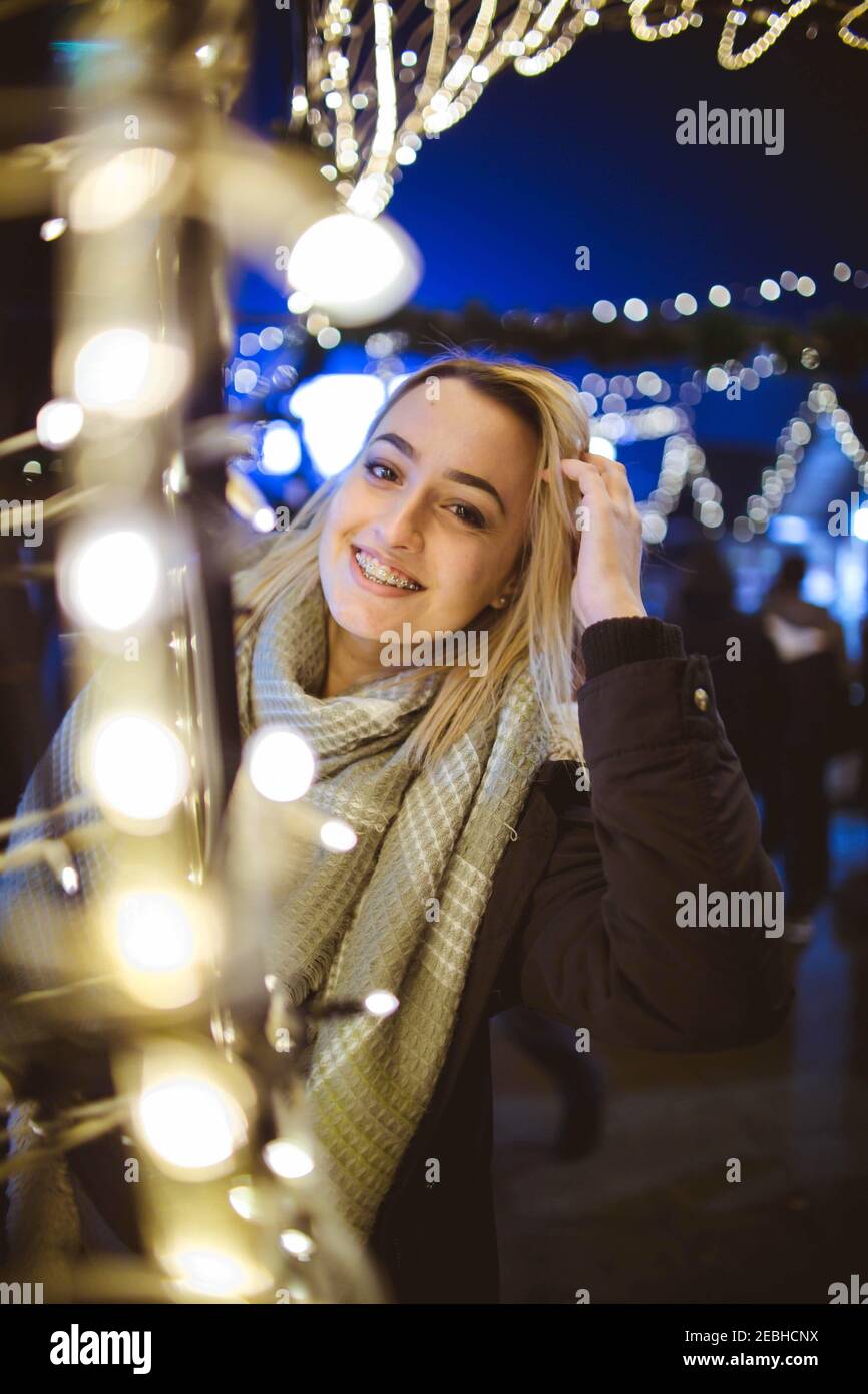Blonde young lady posing for the camera behind the lights in the night ...