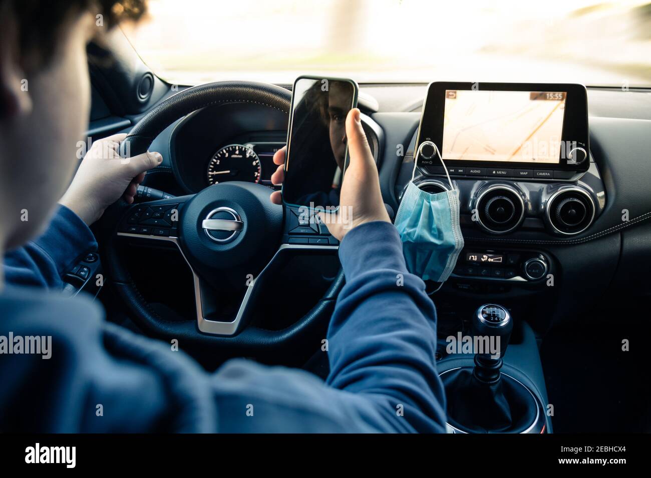 Teen drive a car and use smartphone. Young man reading messages holding ...