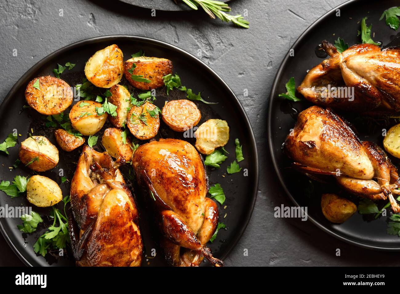 Grilled quails carcasses with potatoes on plate over black stone ...