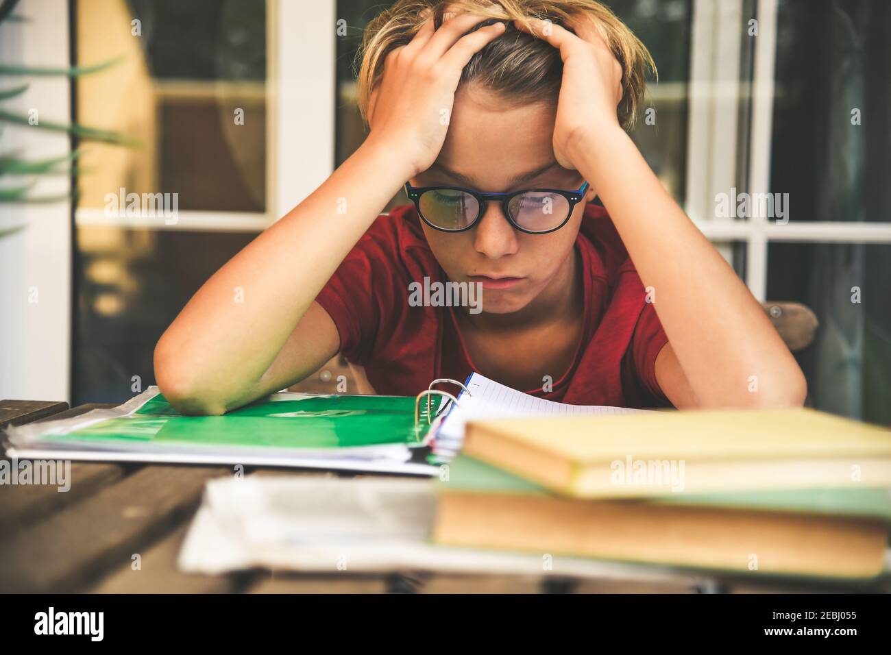 Tired student doing homework at home sitting outdoor with school books ...