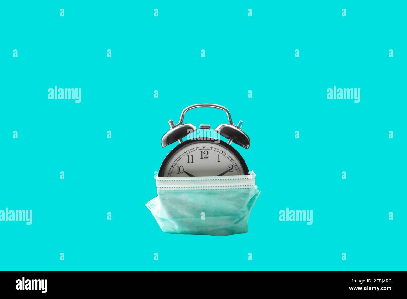 Medical protective mask putting on alarm clock isolated on azure ...