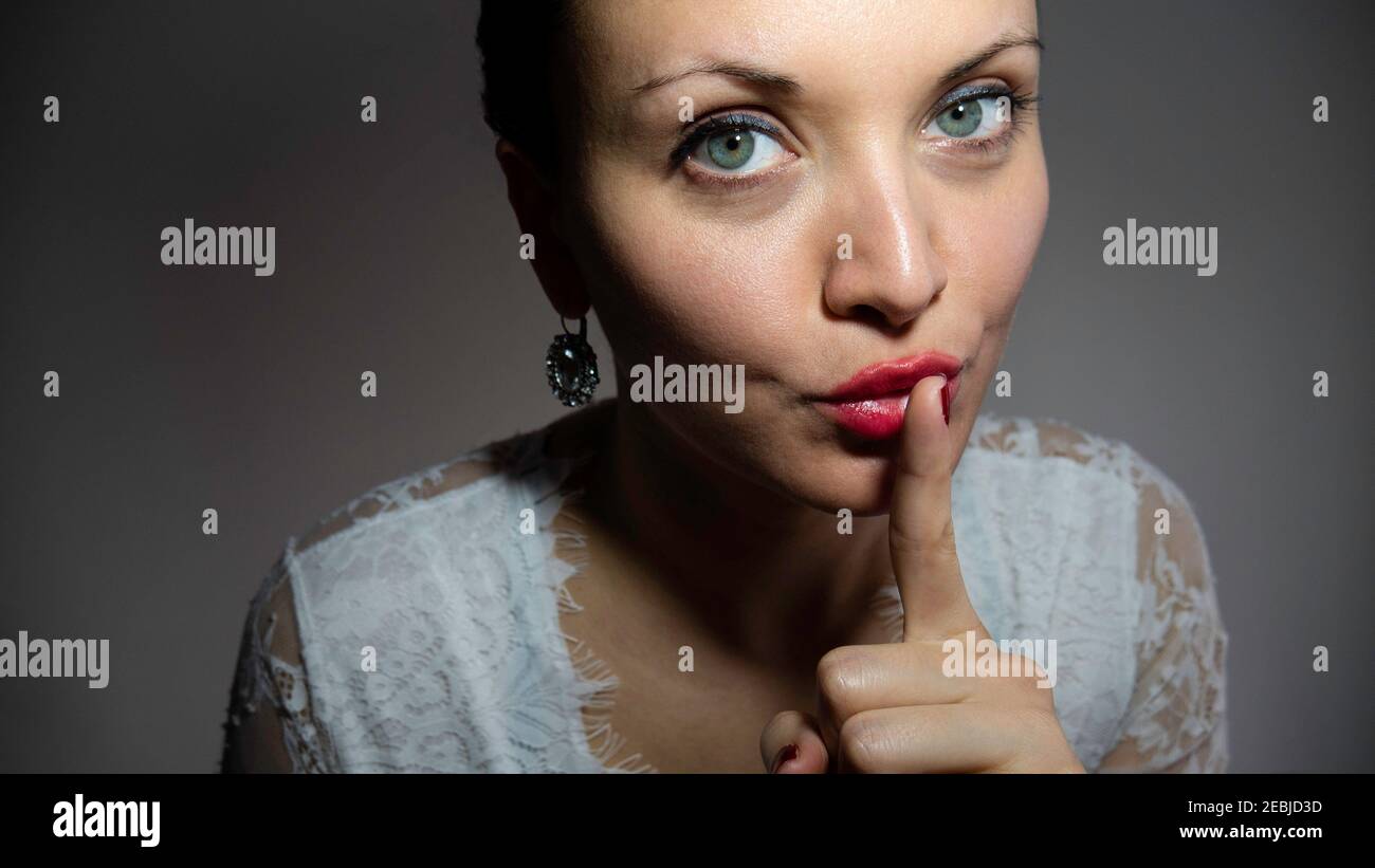 Shh Portrait of mysterious woman showing silence sign holding forefinger on lips Stock Photo - Alamy
