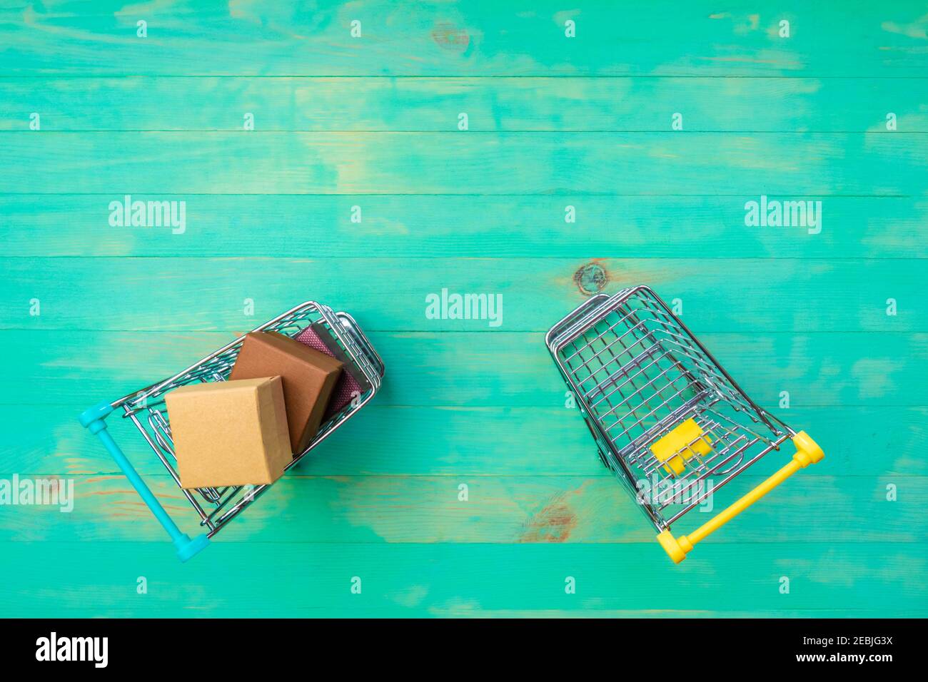 Shopping cart filled with boxes and another one empty on wooden ...