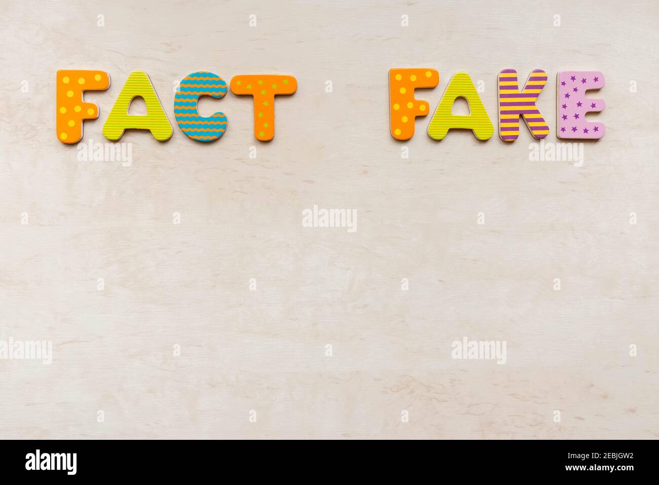 Words FACT and FAKE forming of colorful wooden letters on beige wood ...