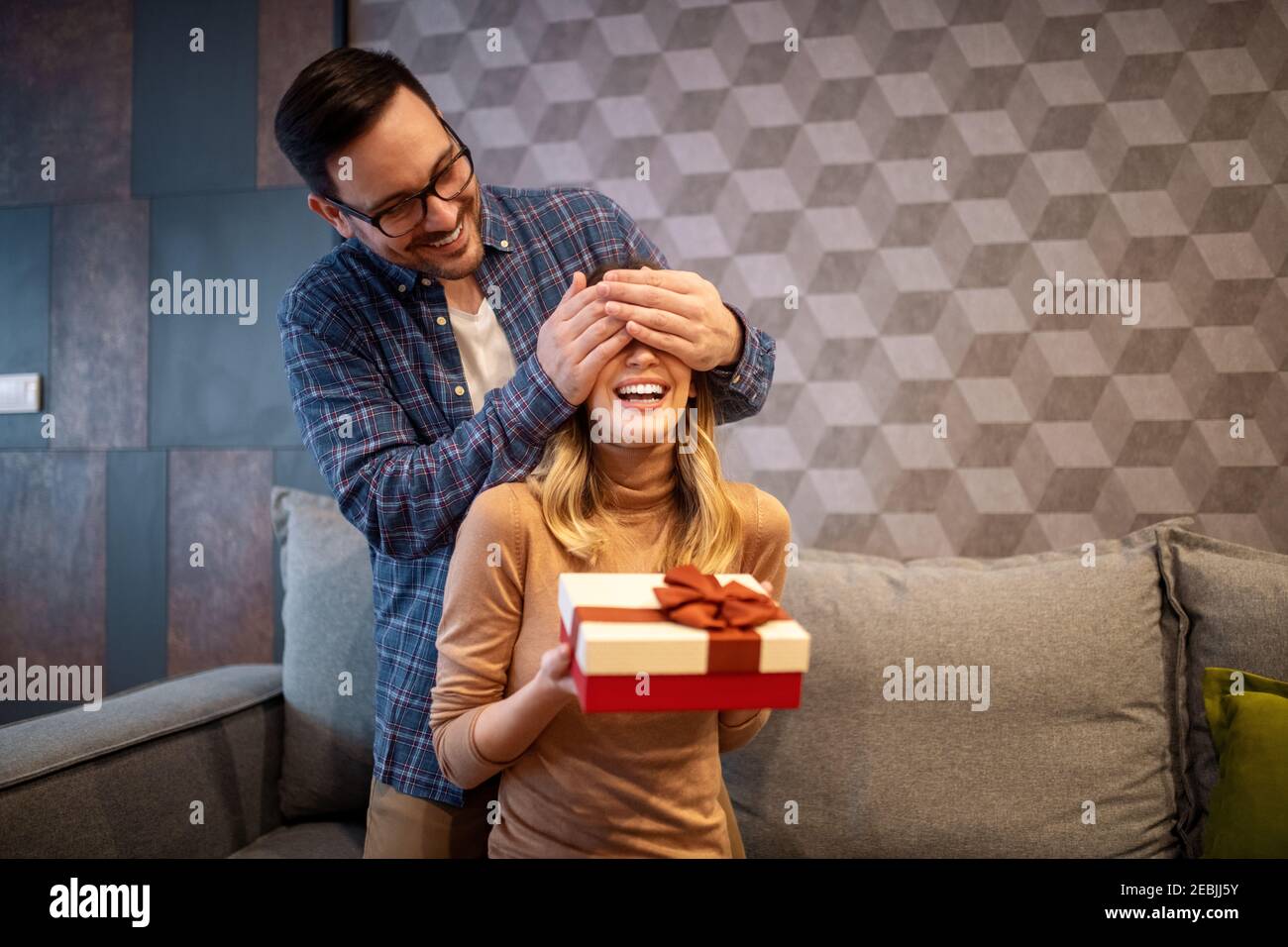 Young girl receiving a surprise gift box from her boyfriend at home ...