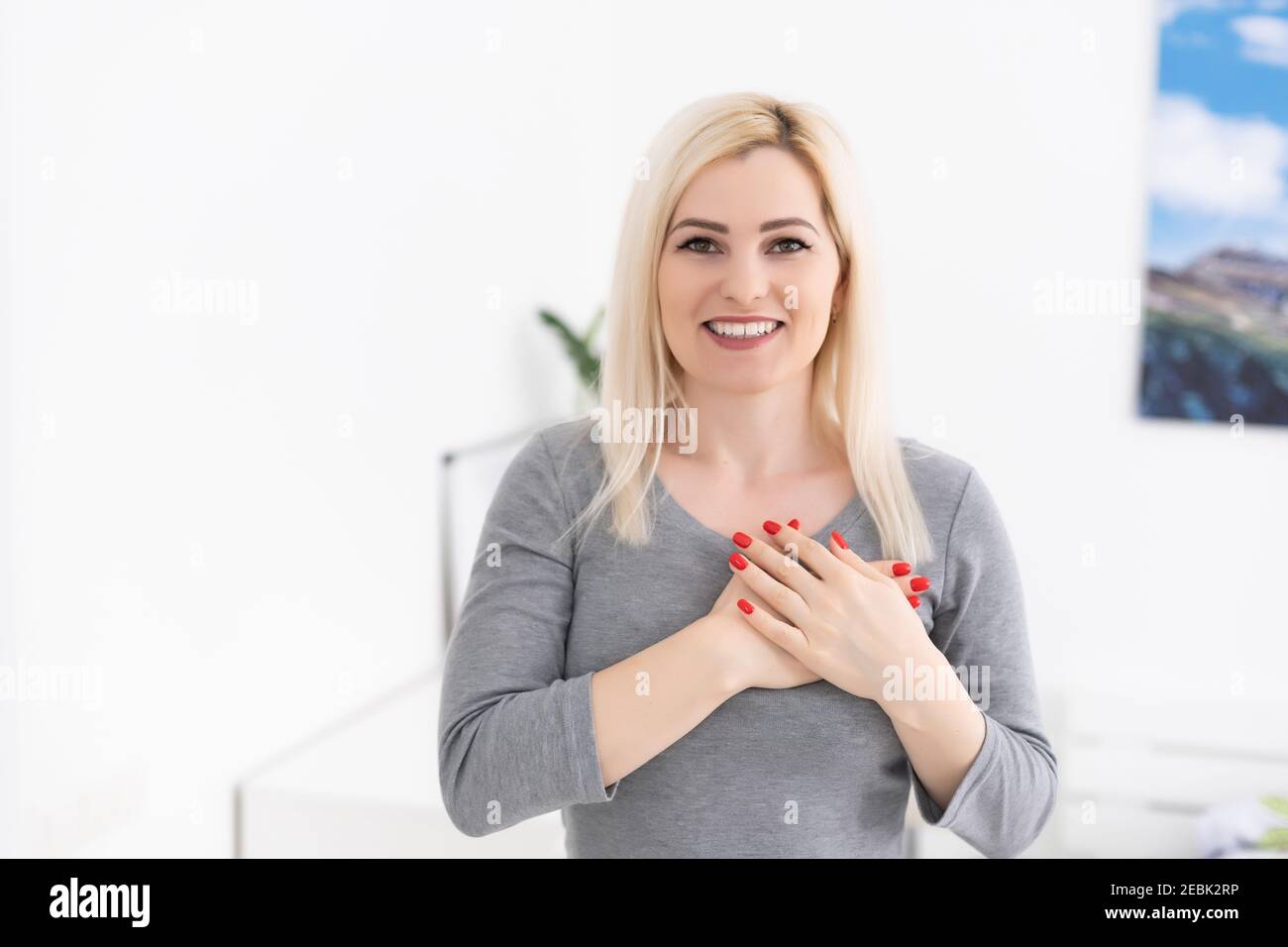 Faithful woman keeps hands on chest near heart, shows her kindness or ...