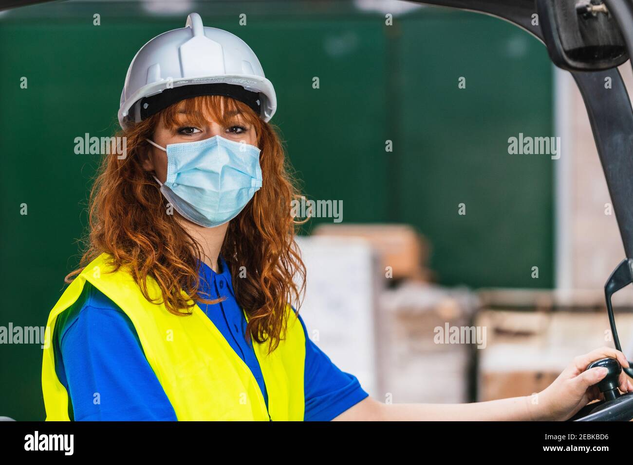 Female industrial worker in a uniform, a hard hat, and a protective ...
