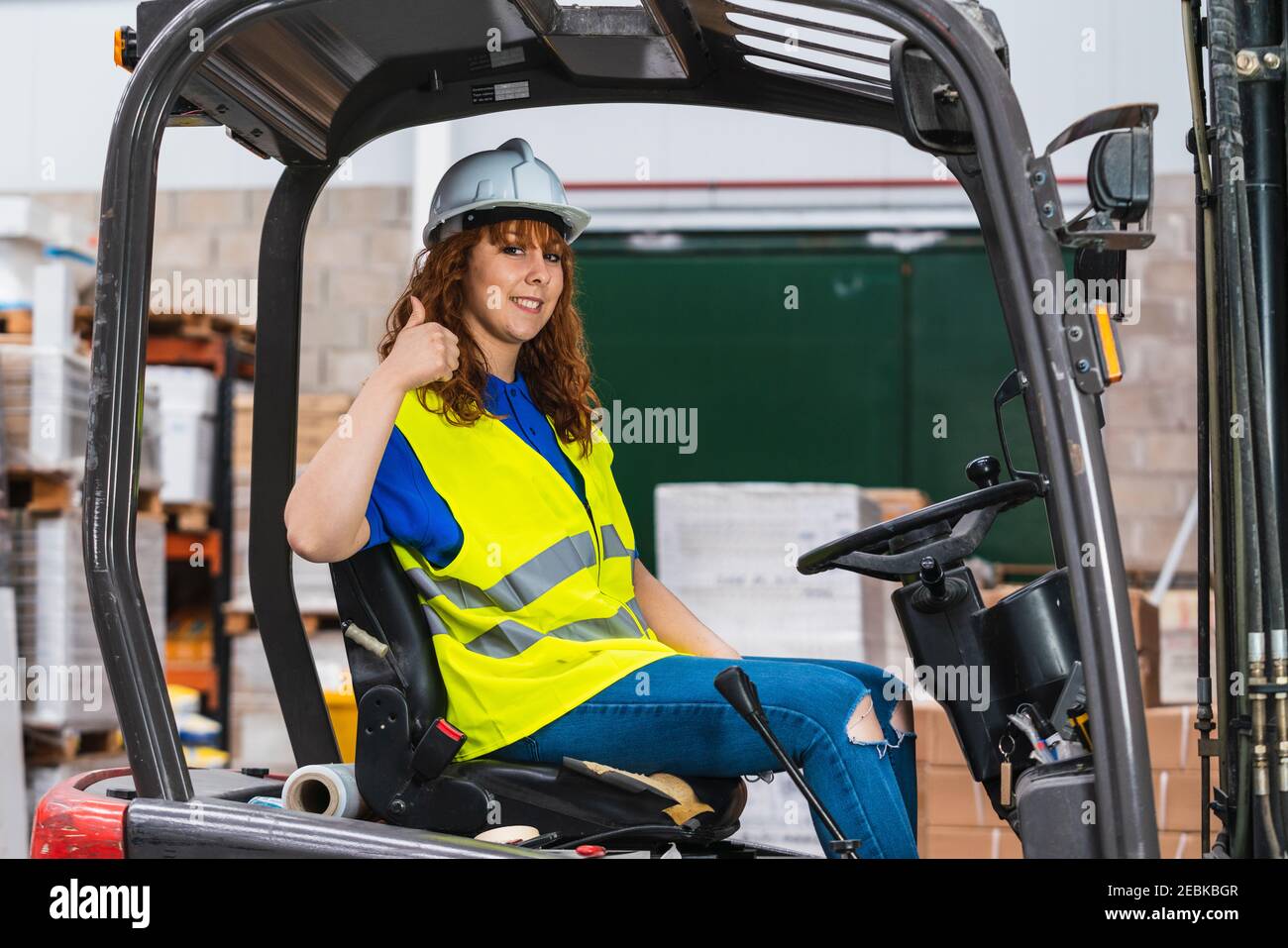 Industrial female worker smiling in a loader at a warehouse Stock Photo ...
