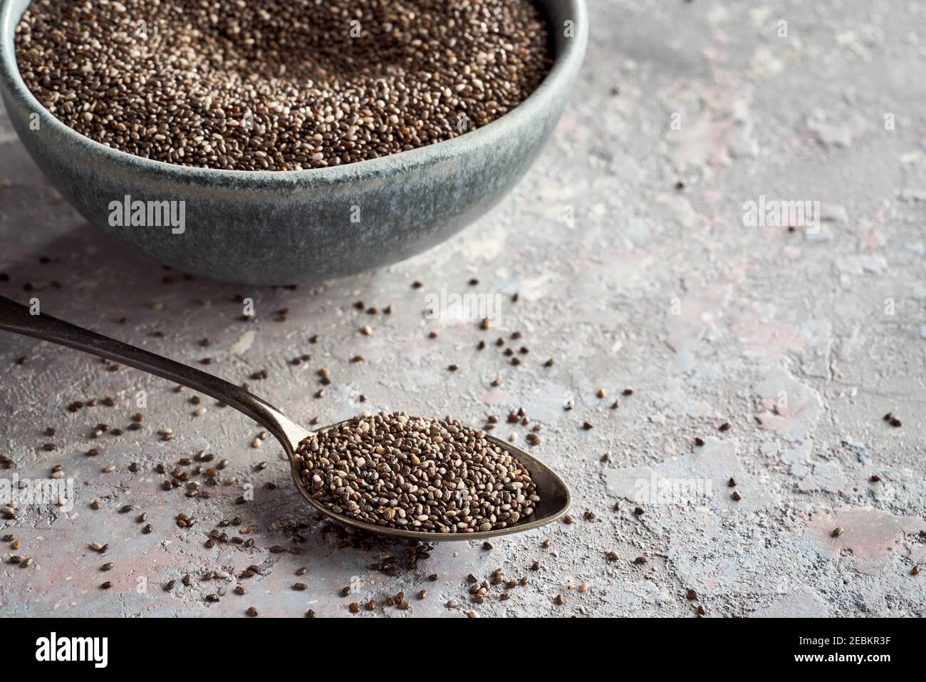 Chia seeds on a metal spoon on a light gray background with copy space ...