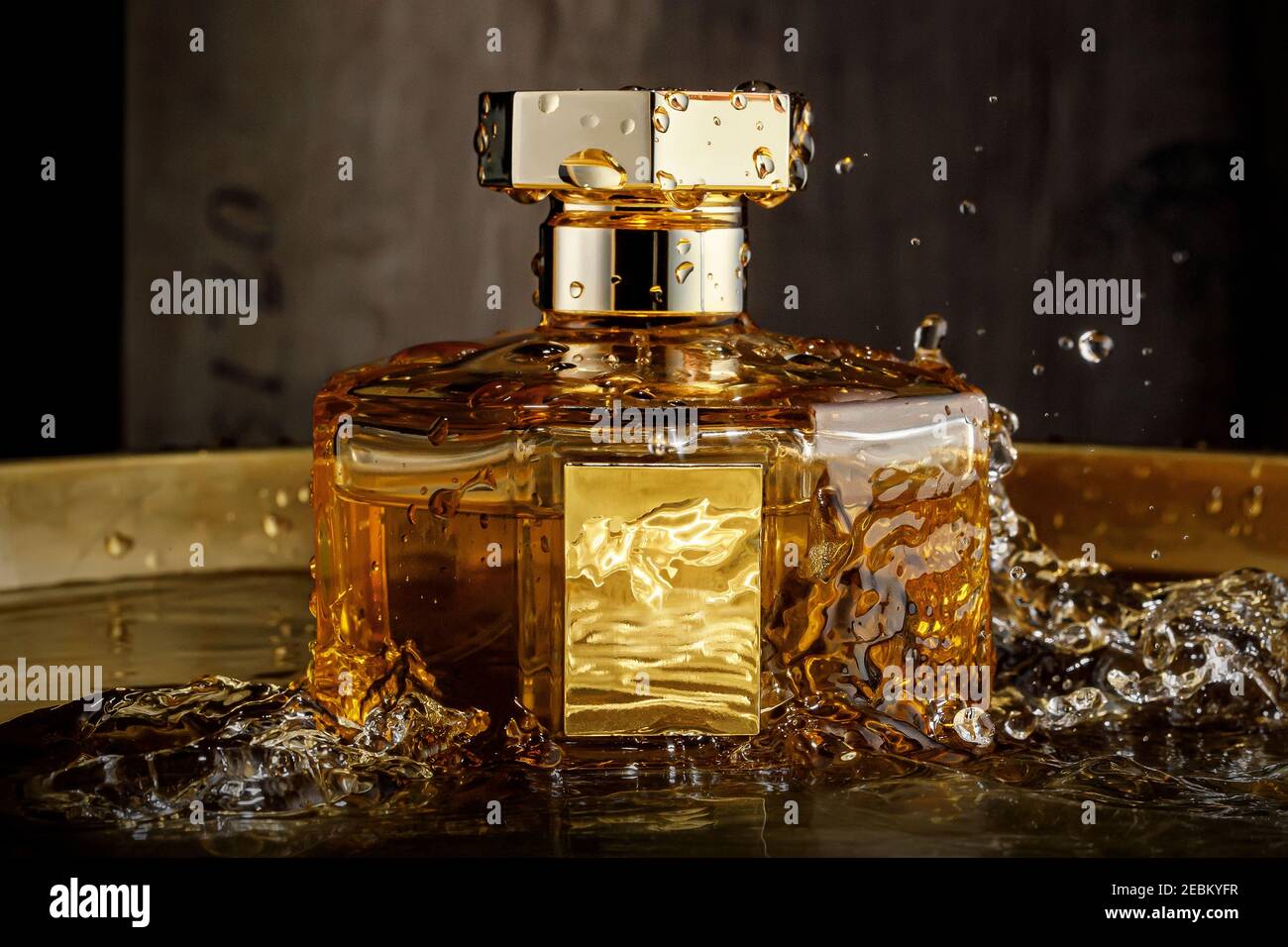 Splashing water around the golden perfume bottle Stock Photo - Alamy
