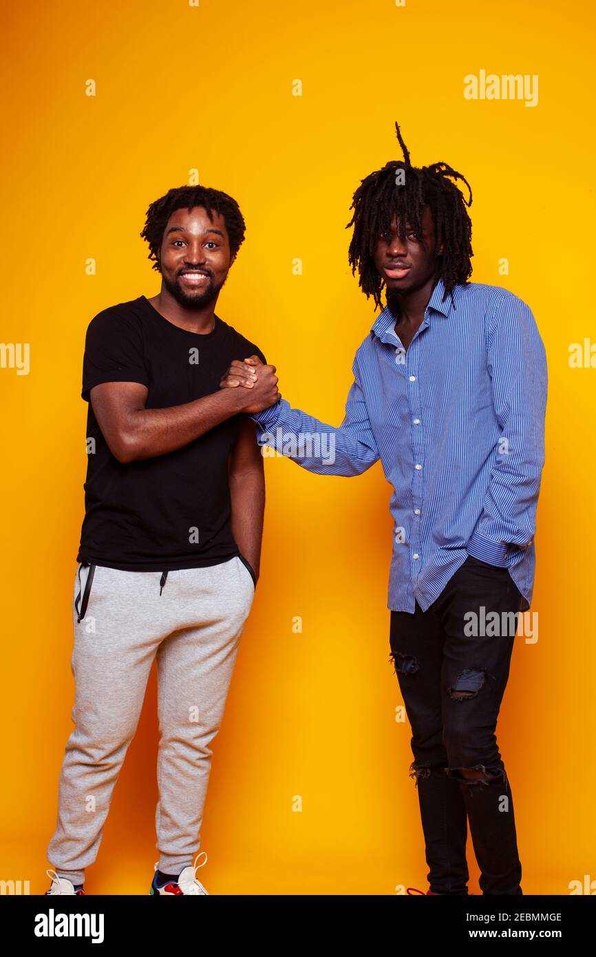 two african american guys posing cheerful together on yellow background ...