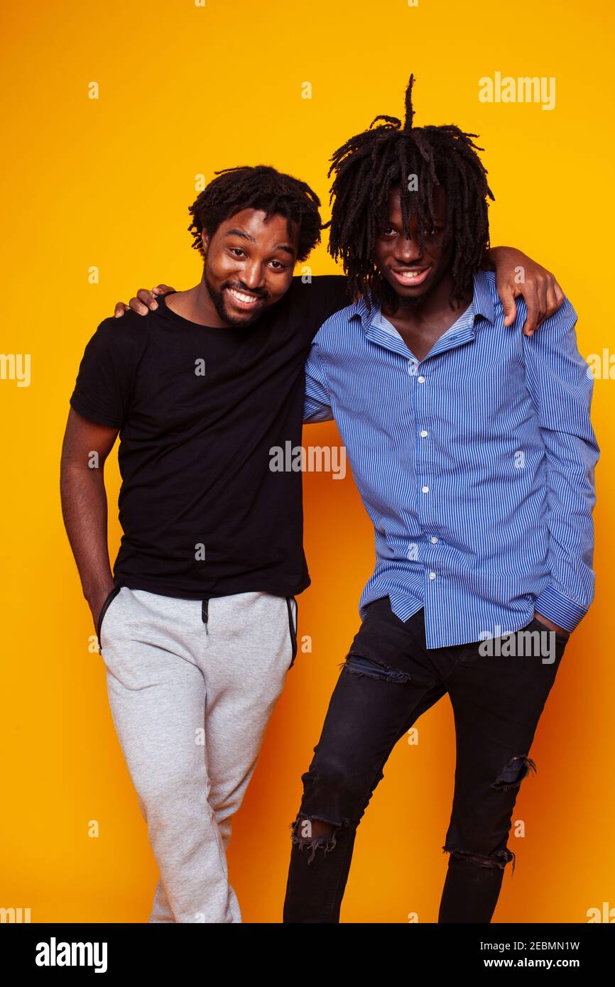 two african american guys posing cheerful together on yellow background ...