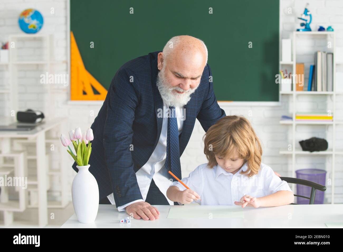 School teacher help to learn. Schoolboy learning in classroom ...