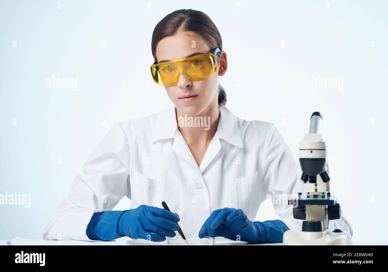 female laboratory assistant in medical gloves and a flask with liquid ...