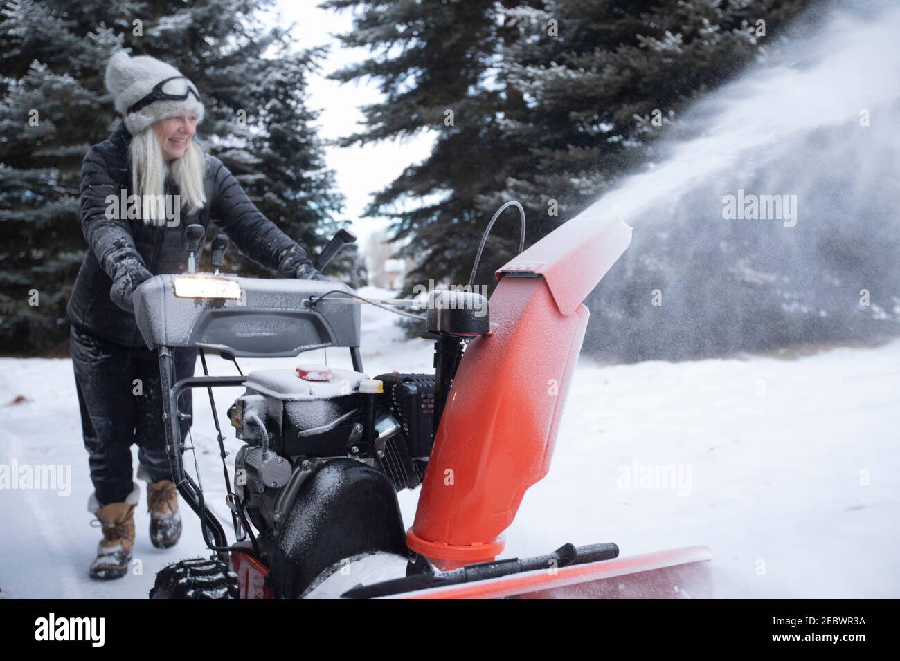 USA, Idaho, Bellevue, Senior woman clearing snow using snowblower Stock ...