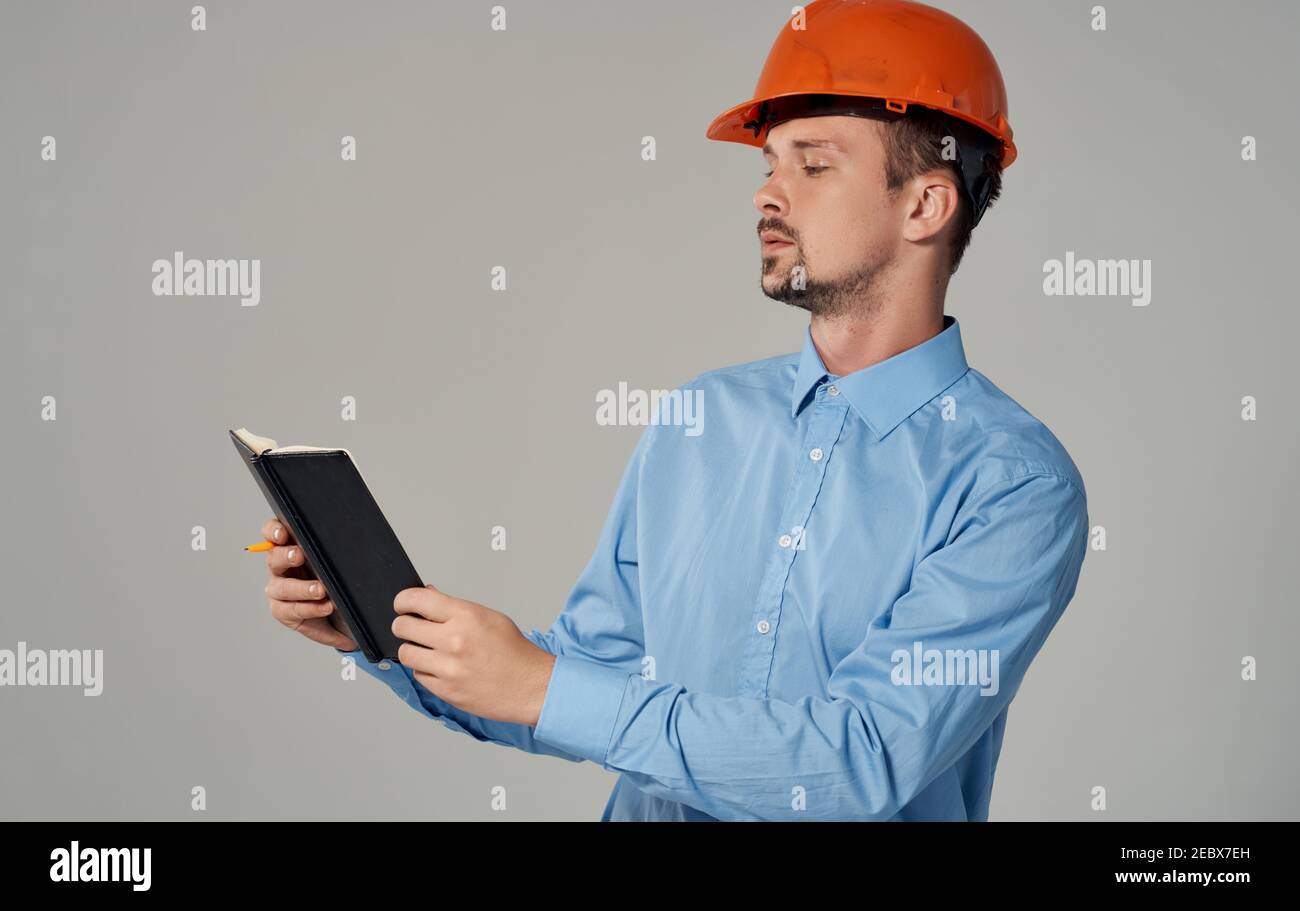 civil engineer in orange hard hat holding documents in hands notepad ...
