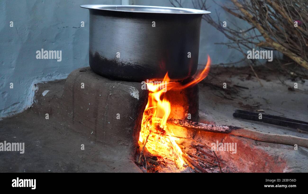 Illuminating reddish wooden fire in clay stove in traditional Indian ...