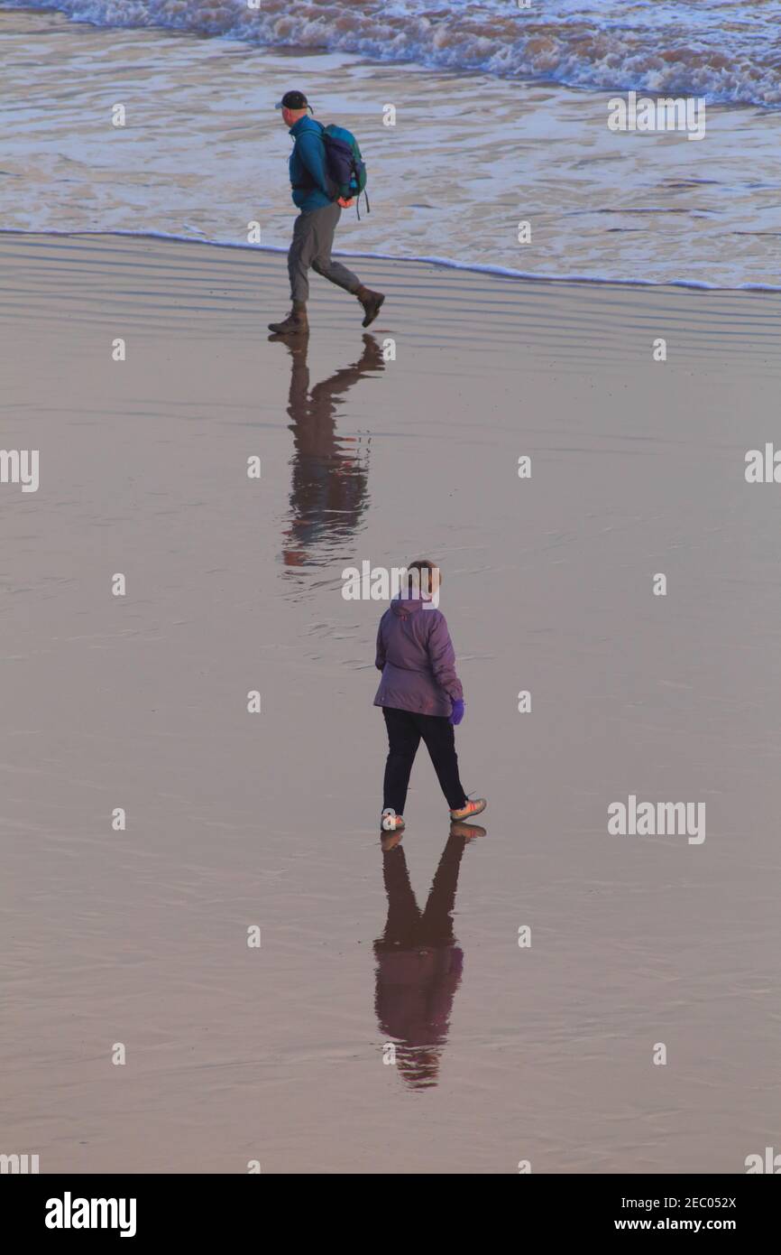 People walk on the sandy beach in town of Sidmouth, Devon. Reflection ...