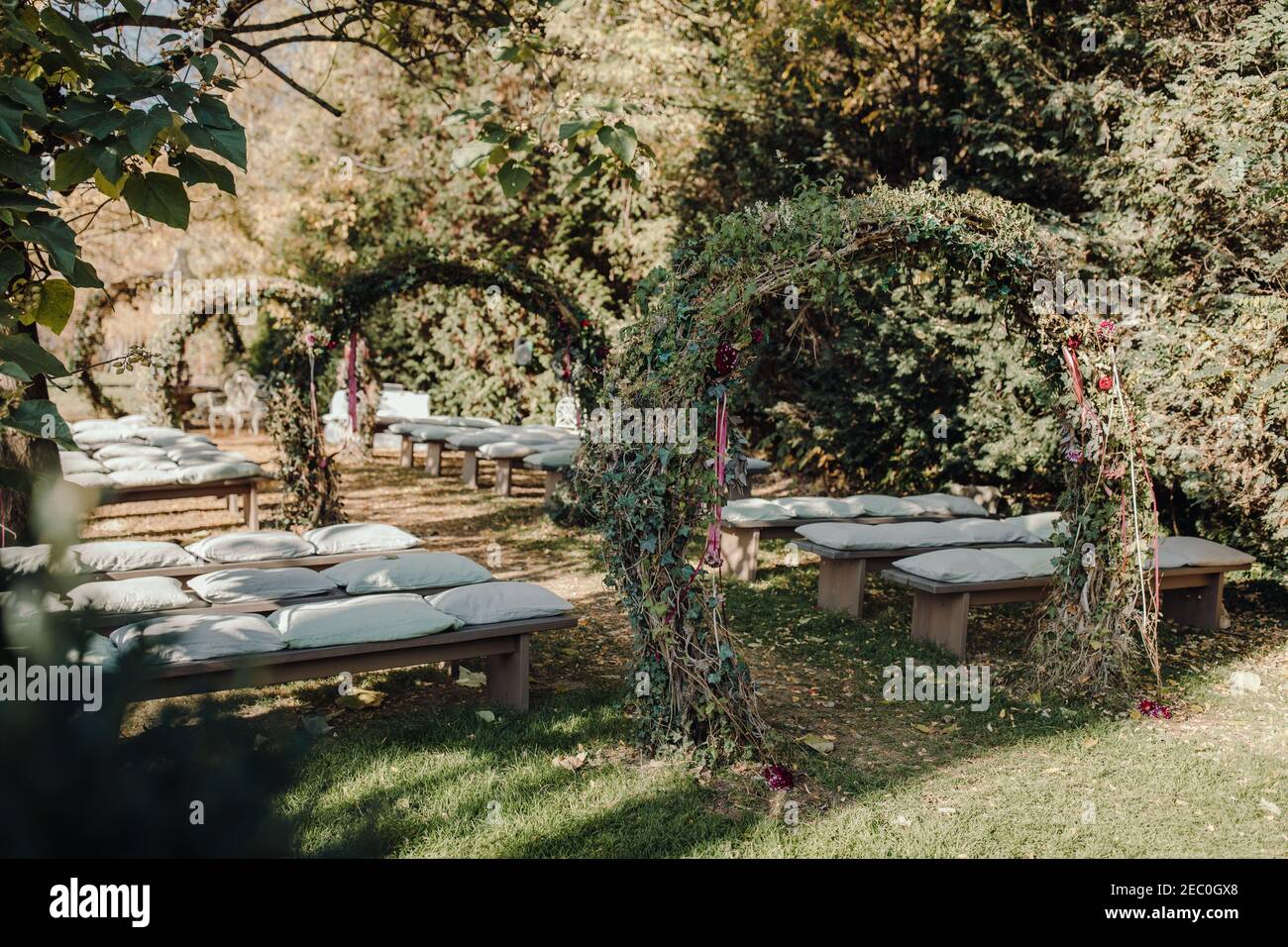 Outdoor wedding setting with flower arches and wooden seats Stock Photo ...
