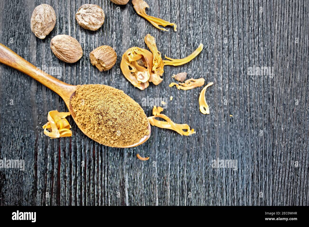 Ground nutmeg in a spoon, whole nuts and dried nutmeg arillus on a ...
