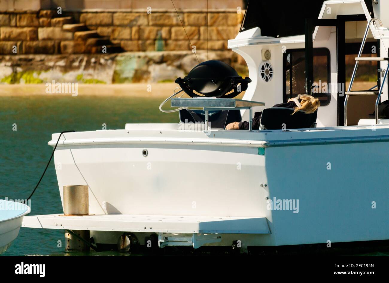 Partial view of a non-descript motorboat with a person sleeping under ...