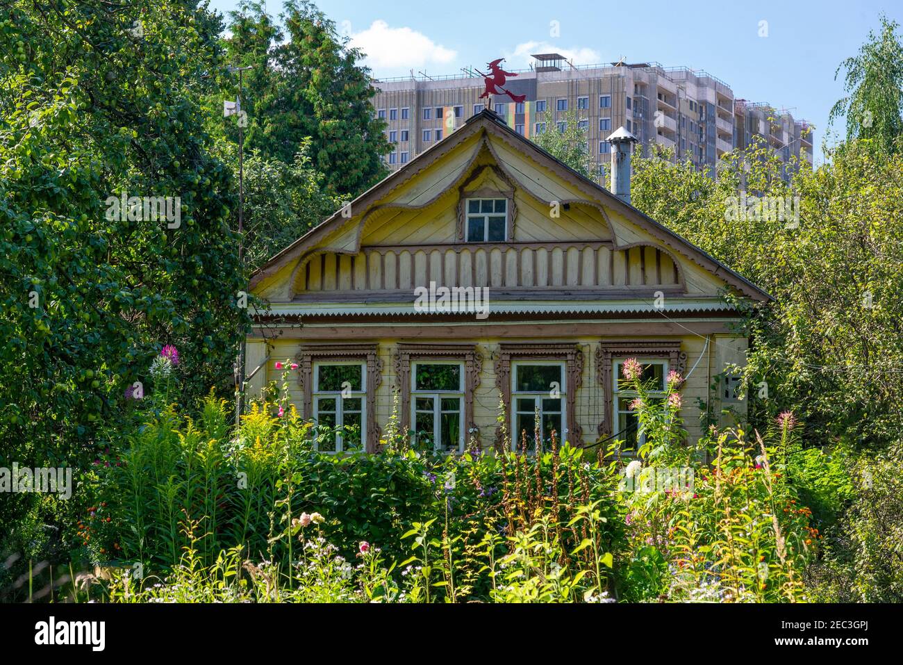 Beautiful rural wooden house on the background of a high-rise building ...