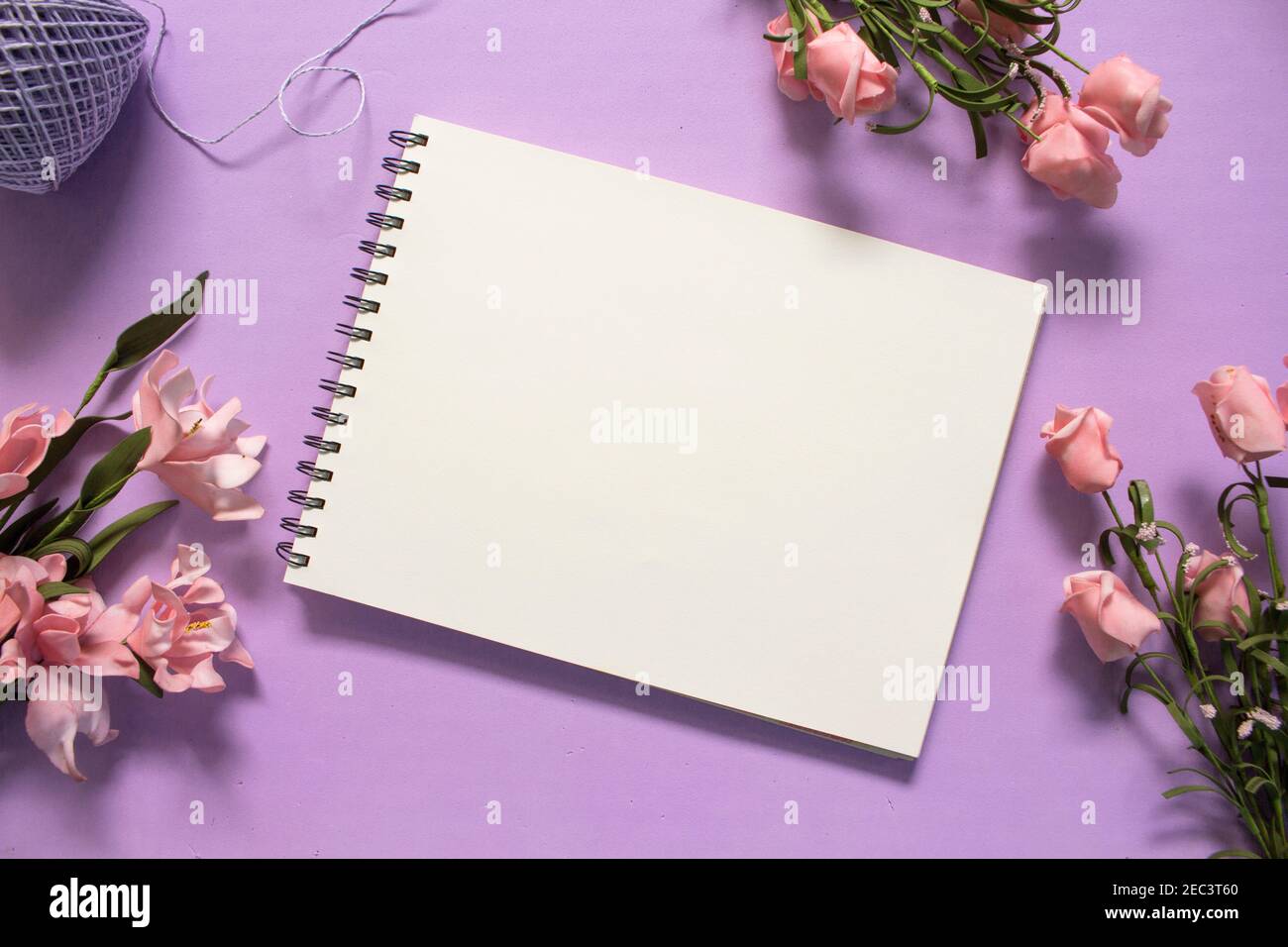 Roses and blank page flat lay on violet background. Romantic pink ...